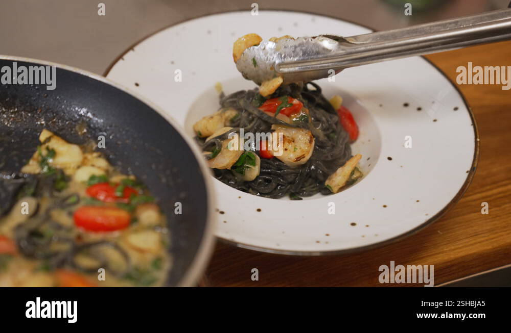Chef completing a dish. Top view of person using cooking tongs to place ...
