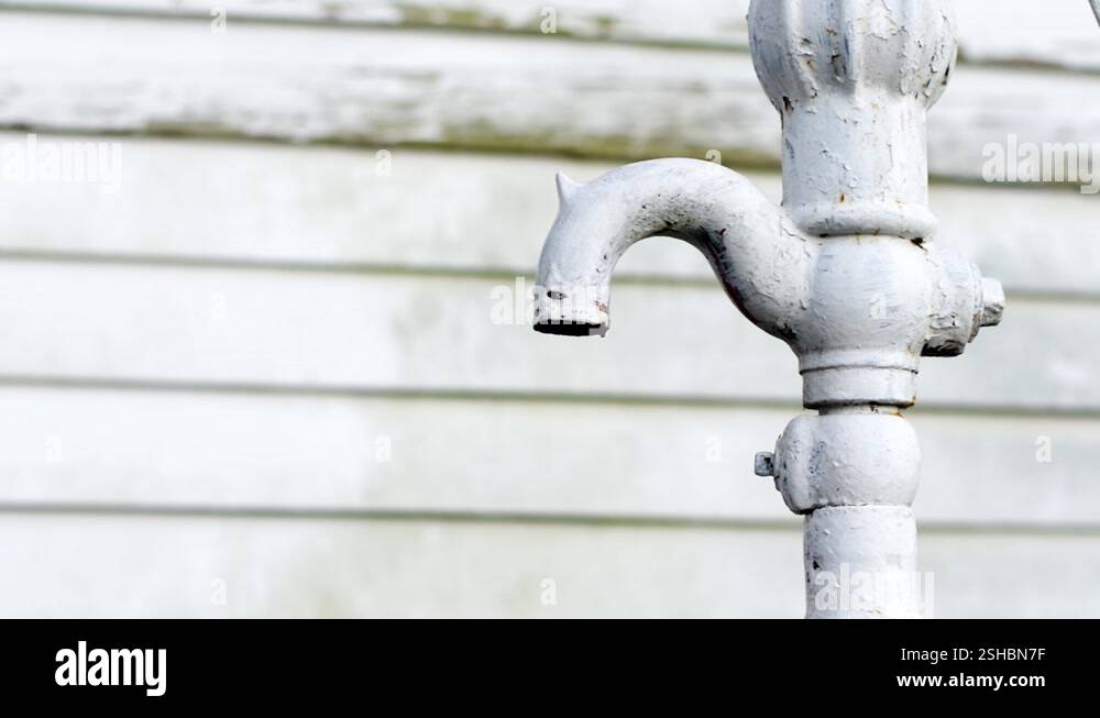 Vintage water tap painted white in front of a white striped wall ...