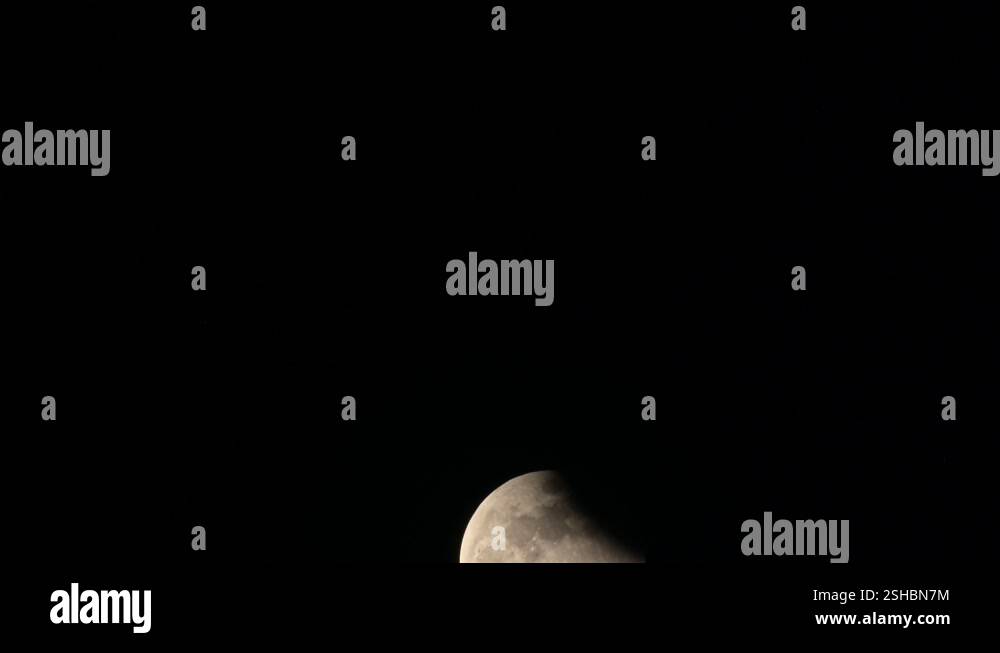 Moon rising from the bottom of the frame partially covered by some ...
