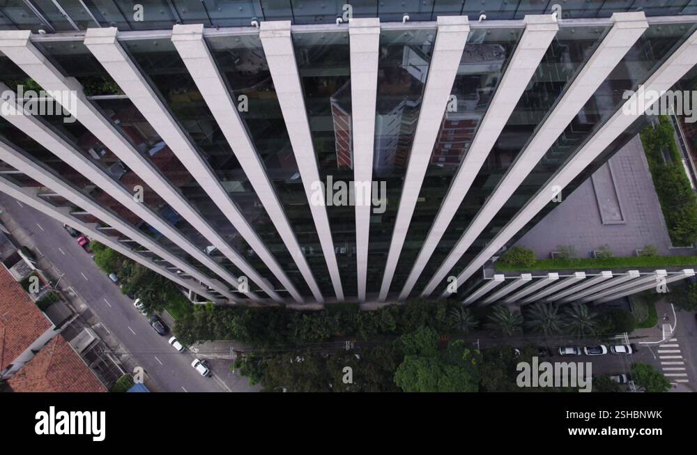 Drone flying up, near a simetrical mirrored building, camera pointing ...