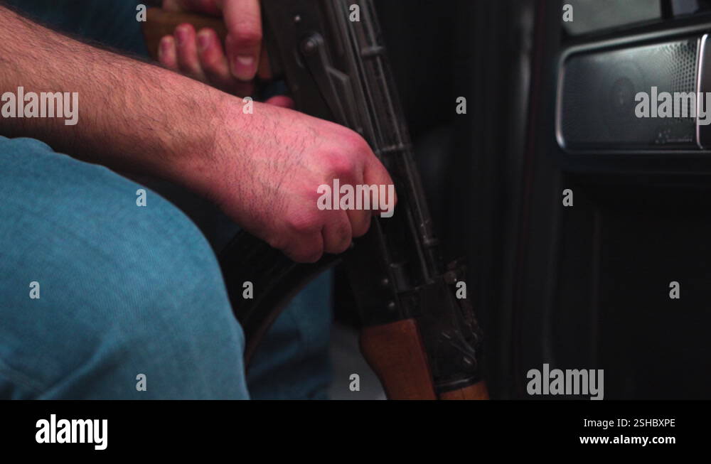 Guy with hairy arms and blue jeans reloading an AK47 riffle gun in a ...