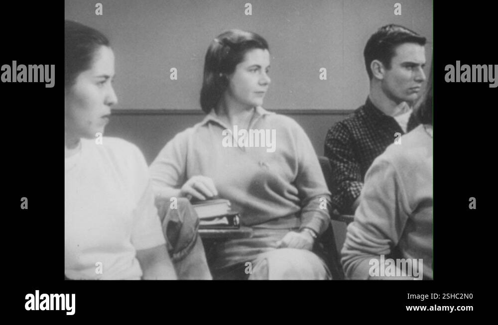 1950s: Students seated in classroom. Student speaks. Woman speaks from ...