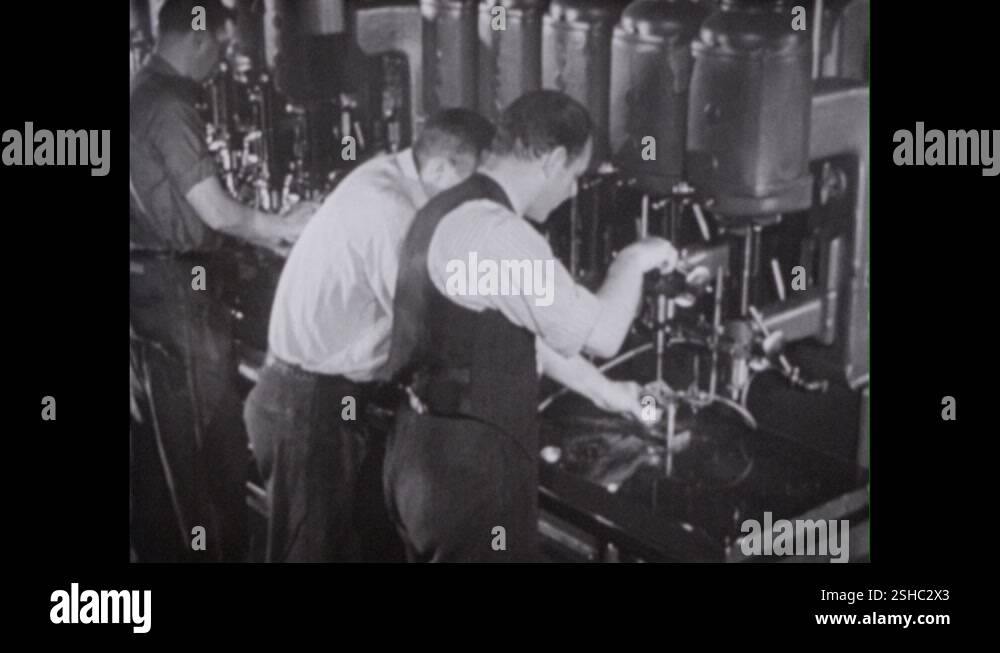 1940s: Hands with tools file lip of metal part. Men work at drill press ...