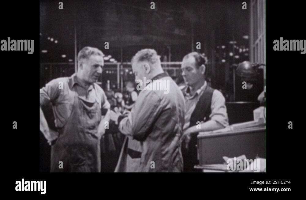 1940s: Foreman writes on paperwork in front of workers. Foreman hands ...