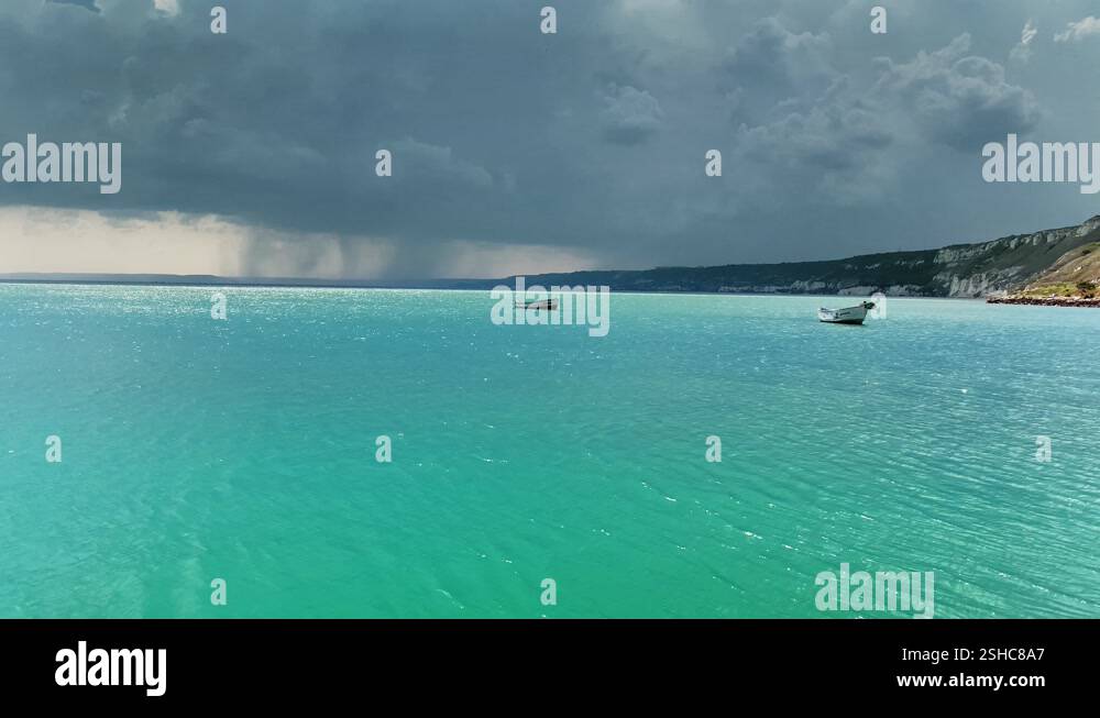 perfect clear blue cyan water and dramatic sky with raiN clouds at the ...