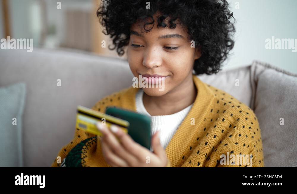 Happy beautiful girl smiling, hold mobile phone and bank card in hands ...