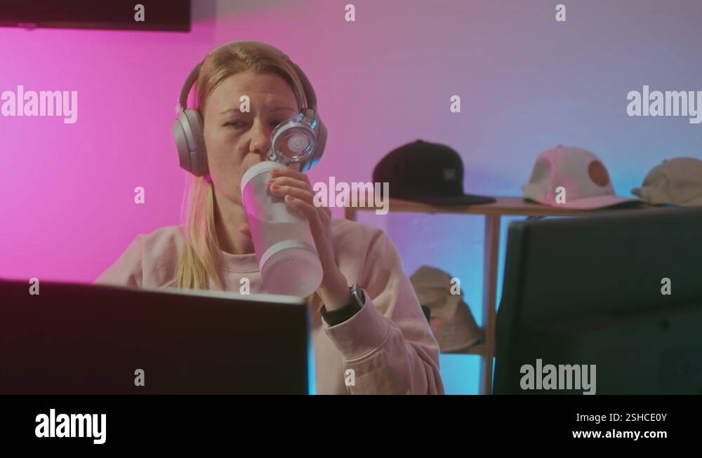 Blonde girl in headset gamer drink water during online game. young ...
