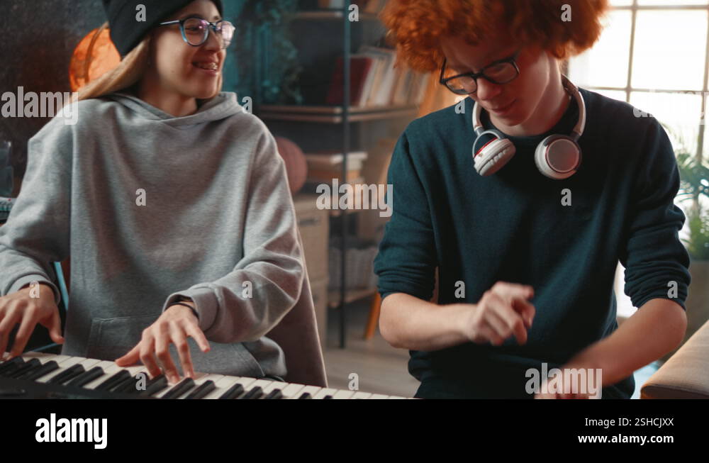 Young teen musicians playing the synthesizer practicing songs together ...
