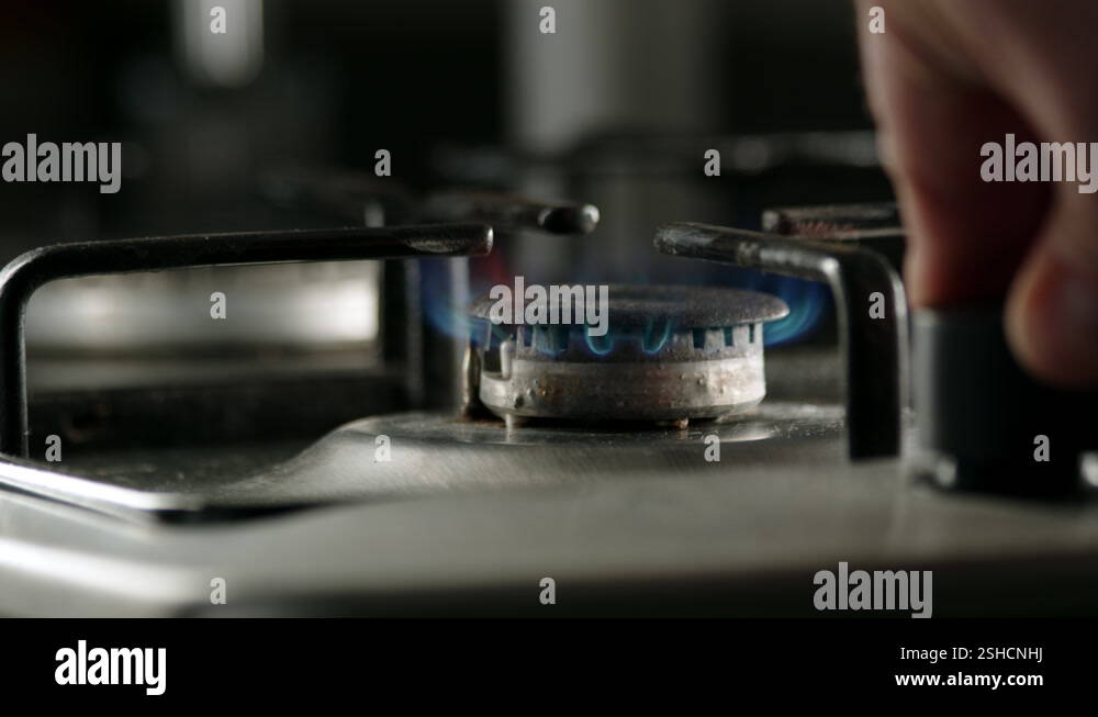 close up view of turning on gas stove, defocused hand turns gas supply ...