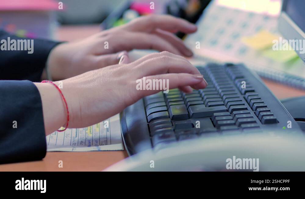 Women's hands with a red thread on the wrist hit the keyboard buttons ...