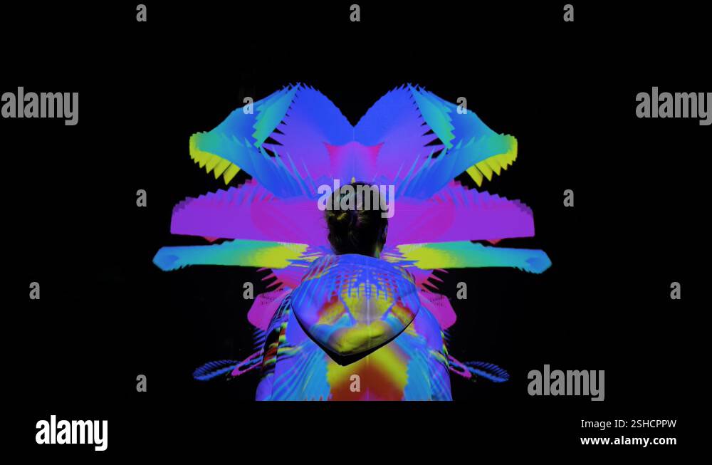 Woman looking around against wall with colorful projector light: back ...