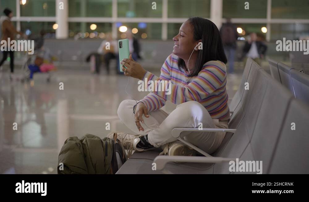 Latin woman making video call at the airport. Concept of waiting times ...