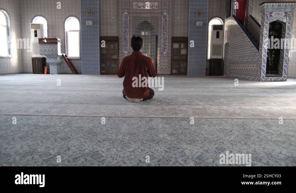 Back view of a young bearded man sitting inside mosque praying to god ...