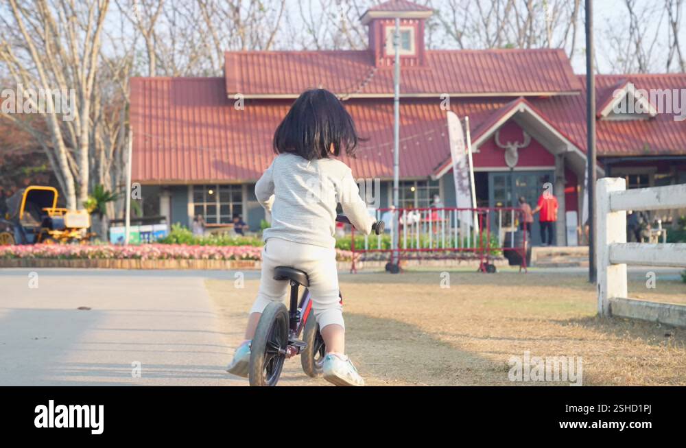 Back behind of a cute little girl child learning to ride first time ...