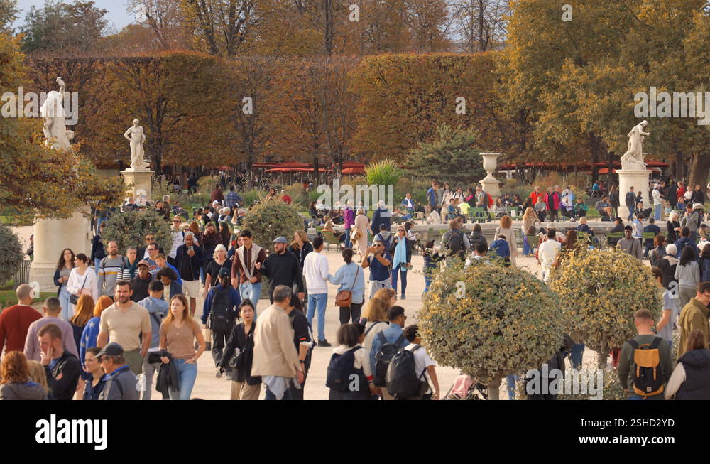 Crowd of tourists walking in the Tuileries garden in Paris, France ...
