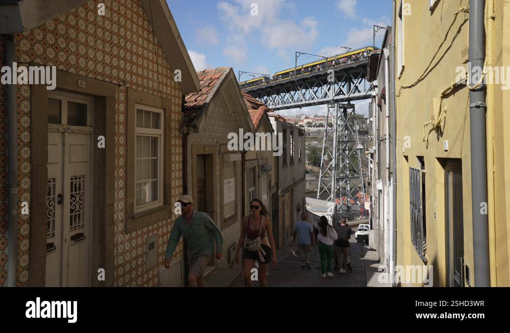 Tram passing over Dom Luis I bridge viewed from colourful narrow street ...