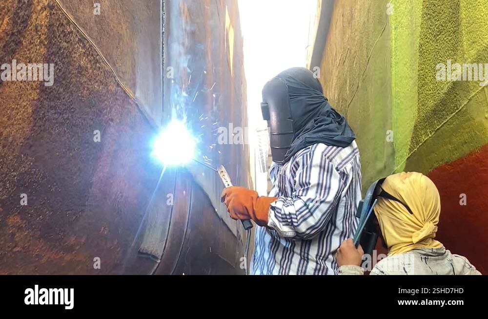 Two worker welding ship hull wearing welding mask for safety. Sparks ...