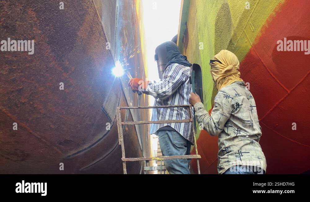 Workers welding ship hull at a dry dock shipbuilding site in Bangladesh ...