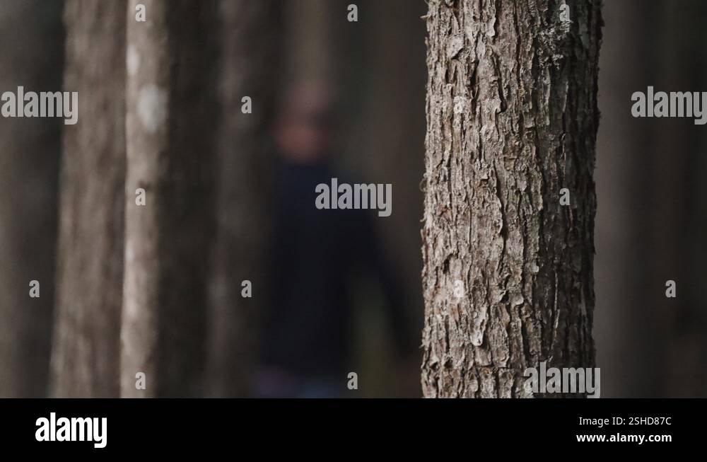 Out of focus male figure walks in slow motion through the background of ...