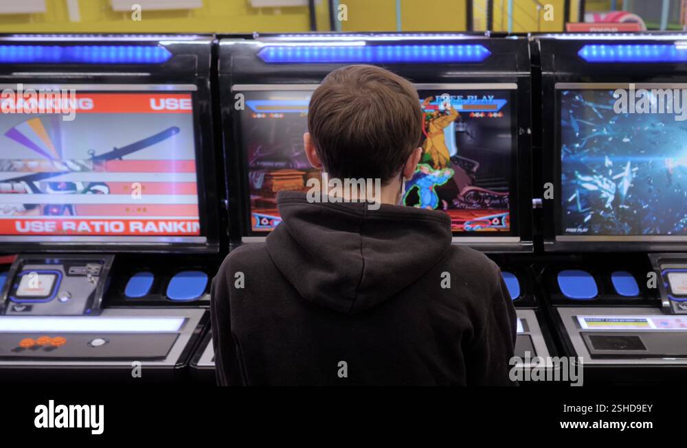 Man playing fighting game arcade machine at gaming hall - back view ...