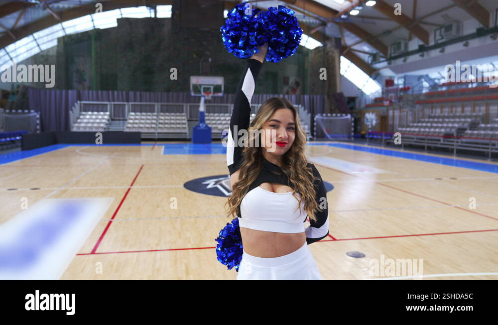Medium shot. A blond cheerleader in an uniform, with one arm behind her ...