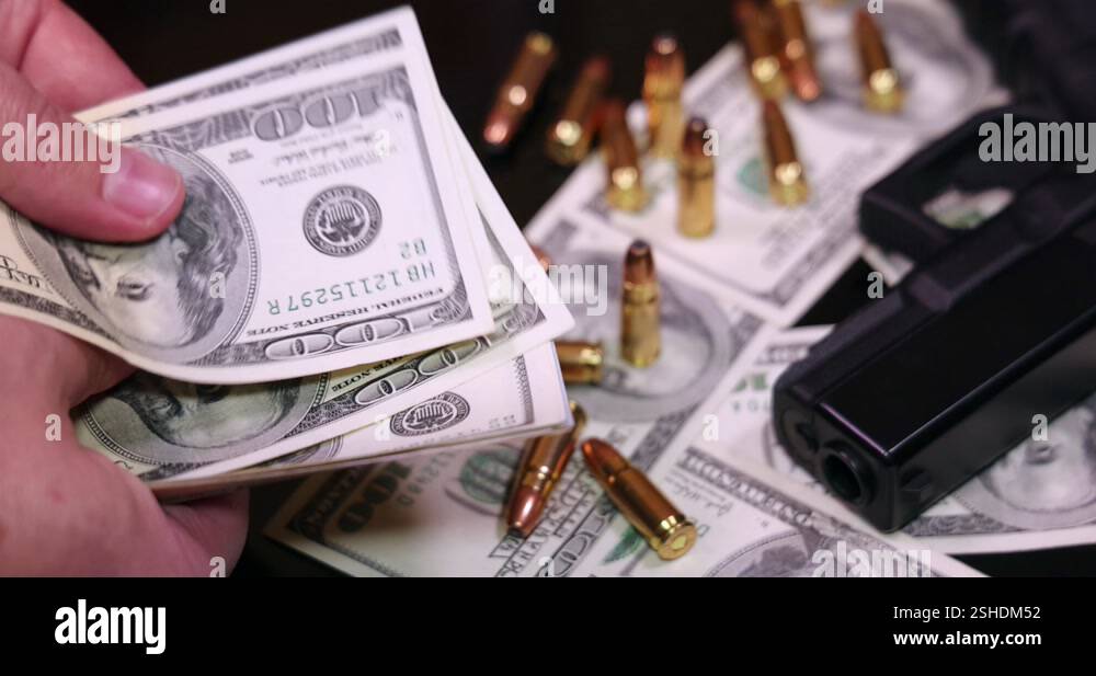 Counting dollar bills, gun and bullets on dollar banknotes background ...
