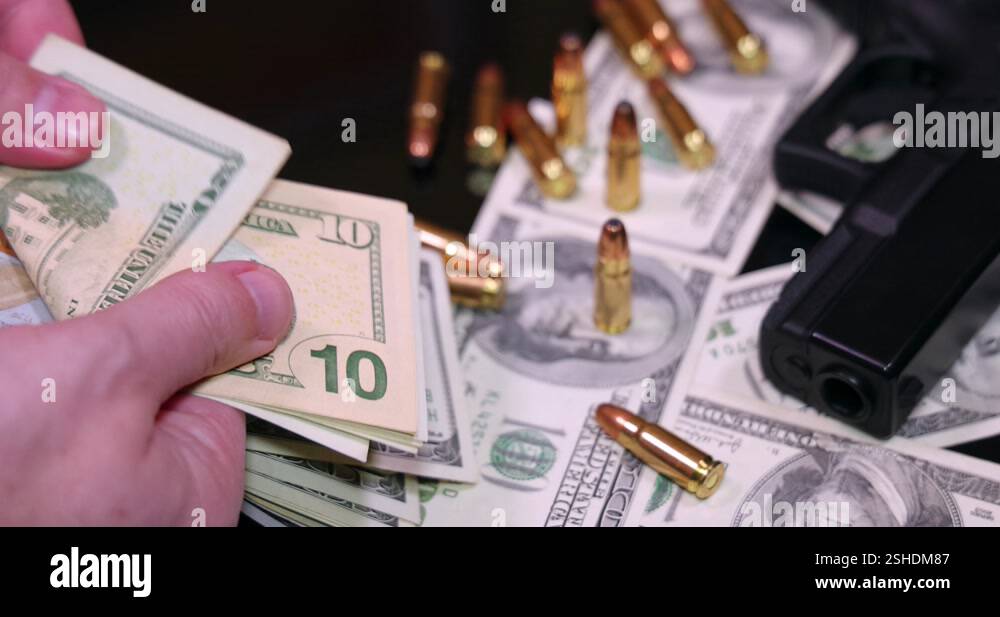 Counting dollar bills, gun and bullets on dollar banknotes background ...