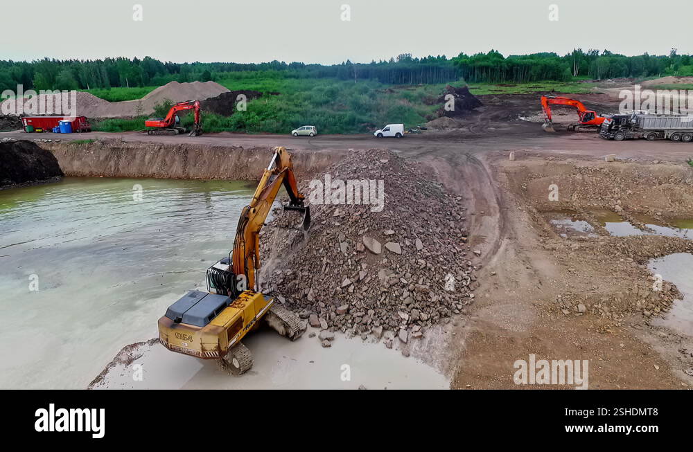 Dredging up rock with an excavator to crush into gravel at a wet quarry Stock Video Footage - Alamy