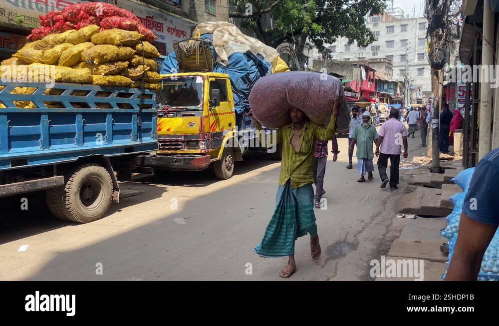 Strong poor laborer man carrying food sack in head to load truck at ...