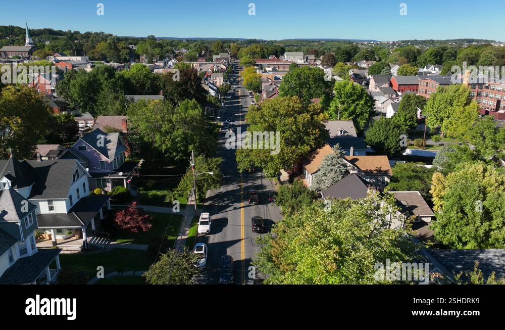Backwards aerial reveal of car driving on small town America street ...