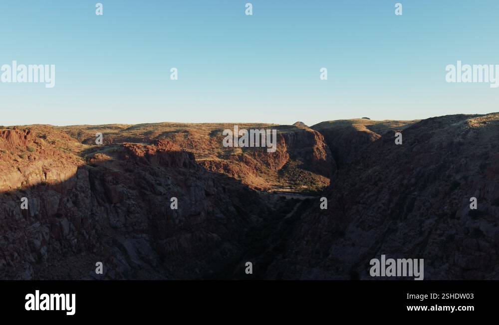 Cinematic aerial view ascending above a lush desert gorge between two ...