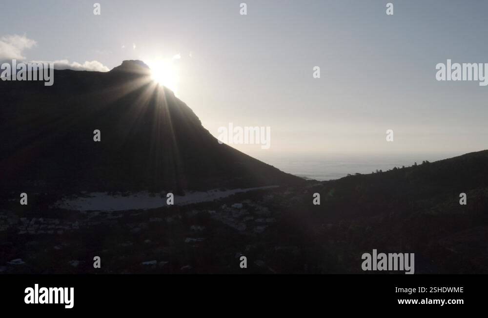 Aerial Mountain Silhouette Tracking Right Revealing Sun Flare at Golden ...