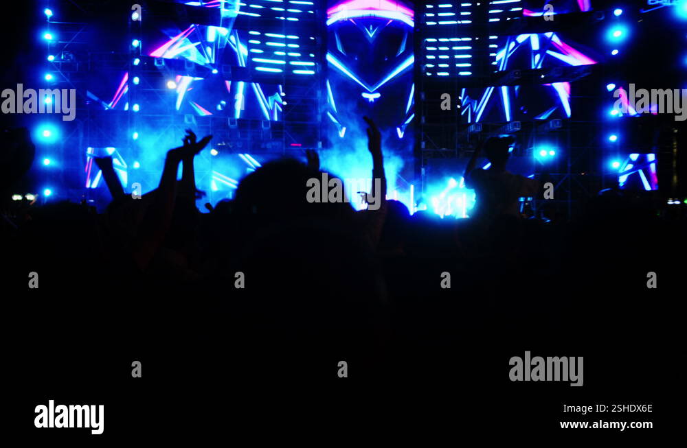 People jump and dance at the evening concert with light show.Fans raise ...