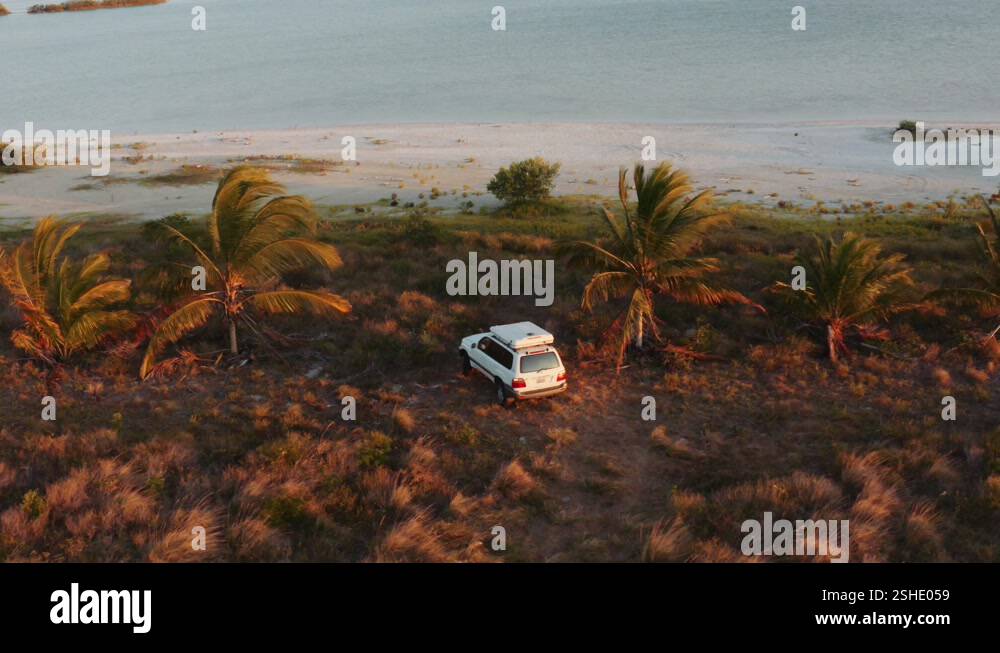 White overland all-terrain SUV with rooftop tent pulls away from its ...