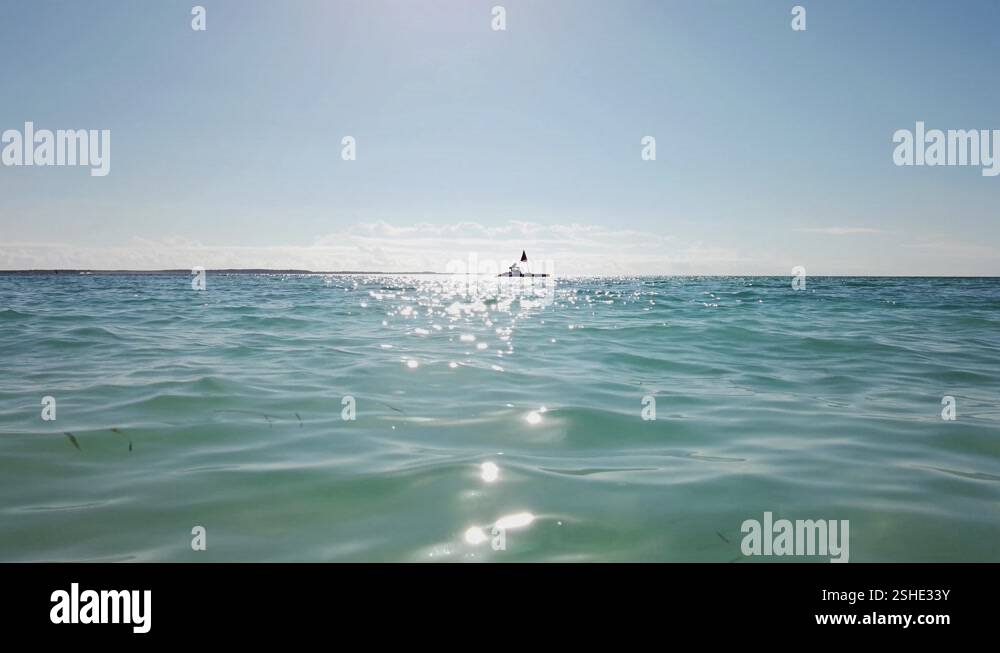 Bright sun in clear blue sky. Tilt down reveal lifeguard on floating ...