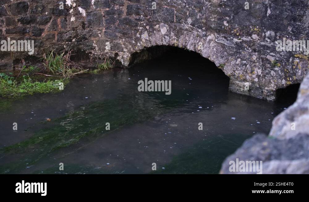 Idyllic, shallow water stream river flowing under old stone arch of ...