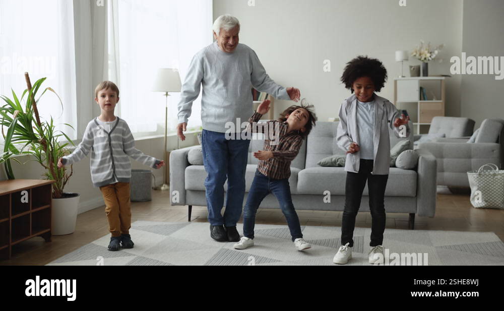 Active great grandfather dancing with three multiethnic grandchildren ...