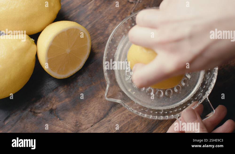 Hand squeezes fresh lemon juice on glass squeezer top down close up Stock Video Footage - Alamy