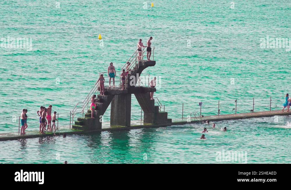 People are jumping of the diving board at the seawater swimming pool at ...