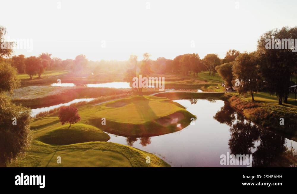 A rising Aerial establishing drone shot shows a golf course with ponds ...
