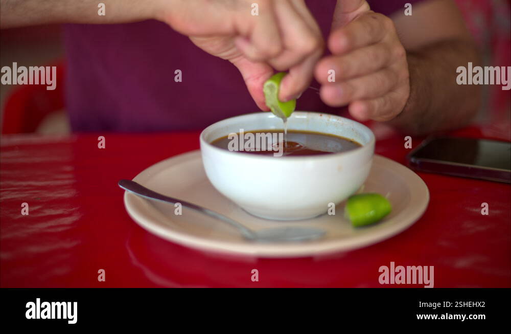 Close up slow motion of a Latin man squeezing lime into his barbacoa ...