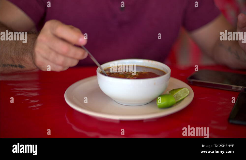 Slow motion close up of a latin man stirring his barbacoa broth with a ...
