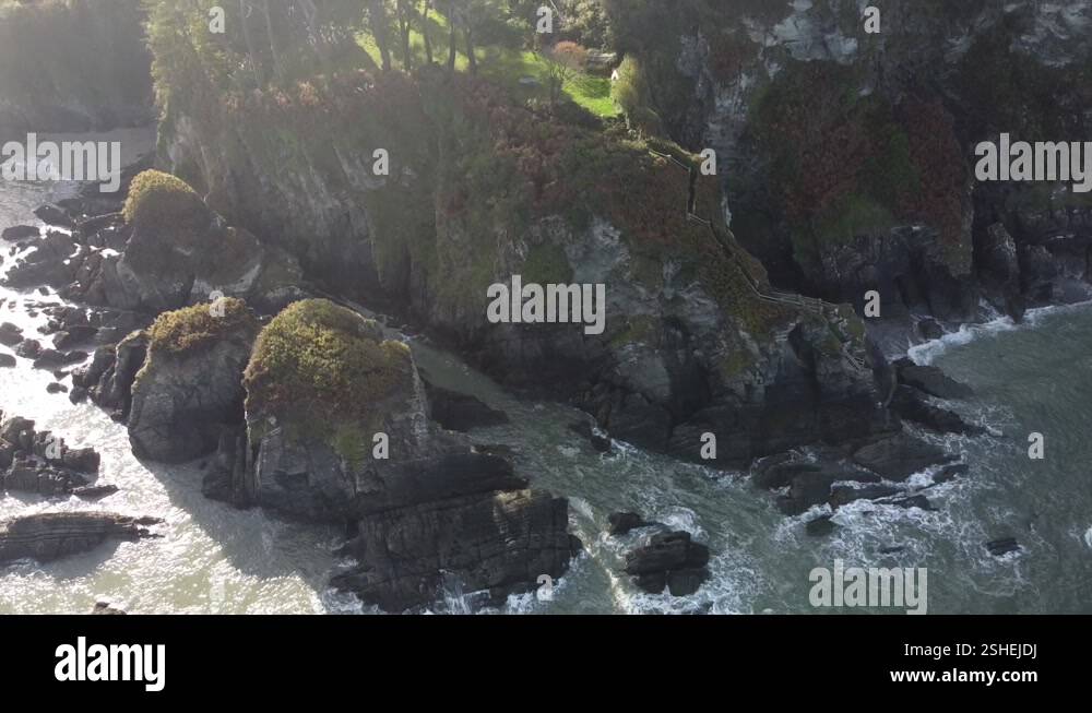 Aerial drone tilt and pan from waves crashing on rock formation to ...