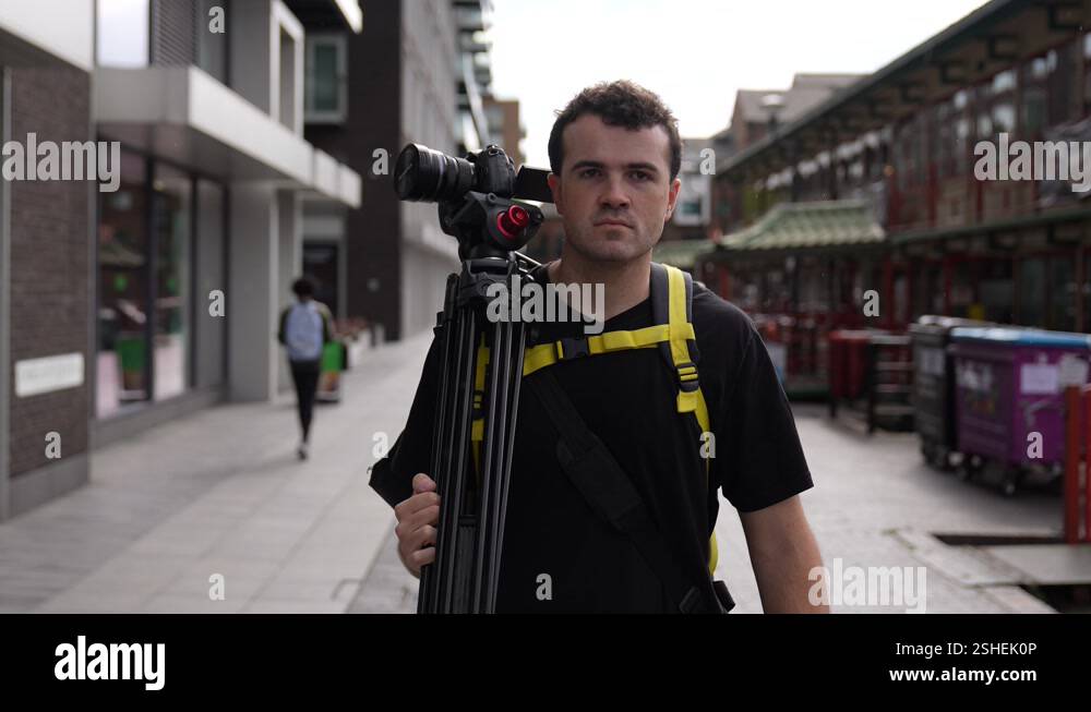 Young man is walking the streets of London with his camera on a tripod ...