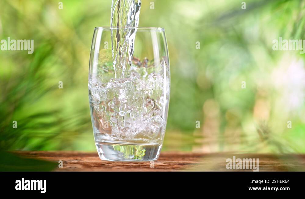 Super Slow Motion Shot of Pouring Pure Water into Glass on Green ...