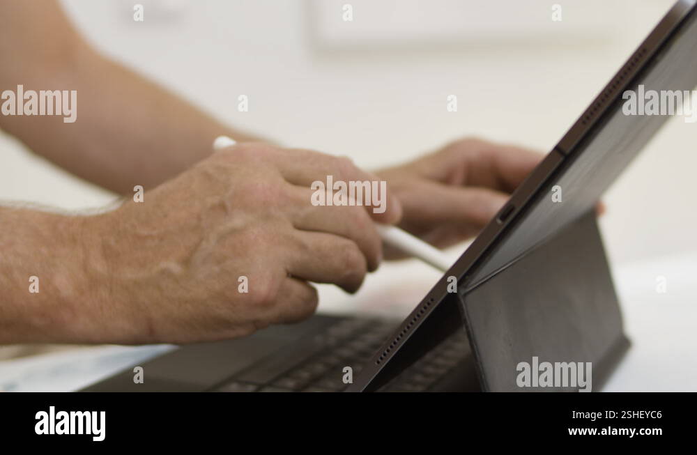Elderly man using iPad tablet with stylus and learning new technology ...