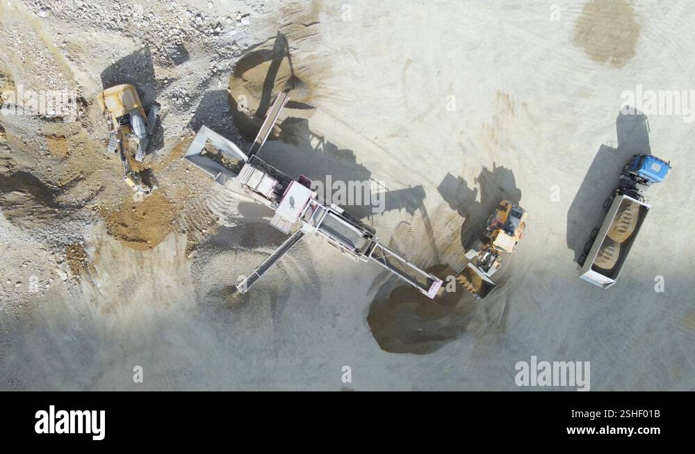 Excavating machine sorting quarry rubble, digger clearing rocks in pit ...