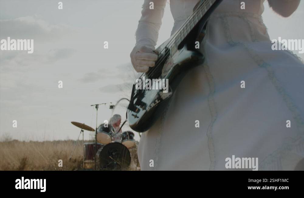 Punk playing bass in wedding dress while drummer is playing in the ...