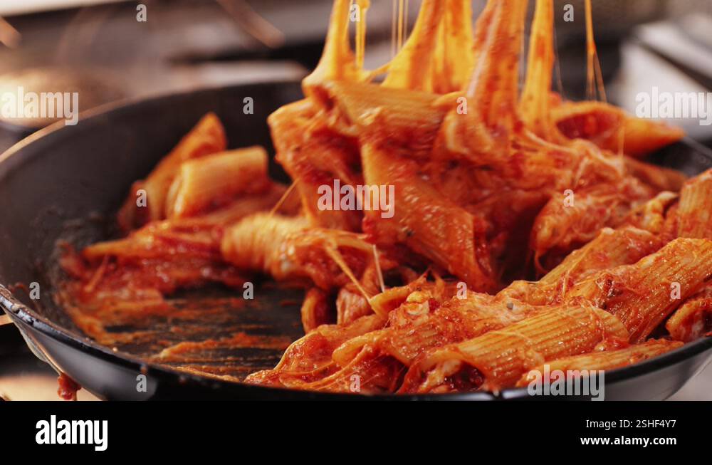 Chef cooking penne pasta with tomato sauce and mozalerra cheese in pan ...