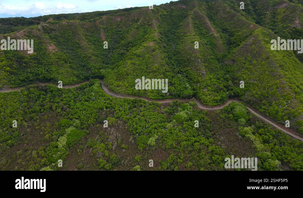 Aerial zoom in on huge mountain in Molokai Hawaii. Winding road in ...